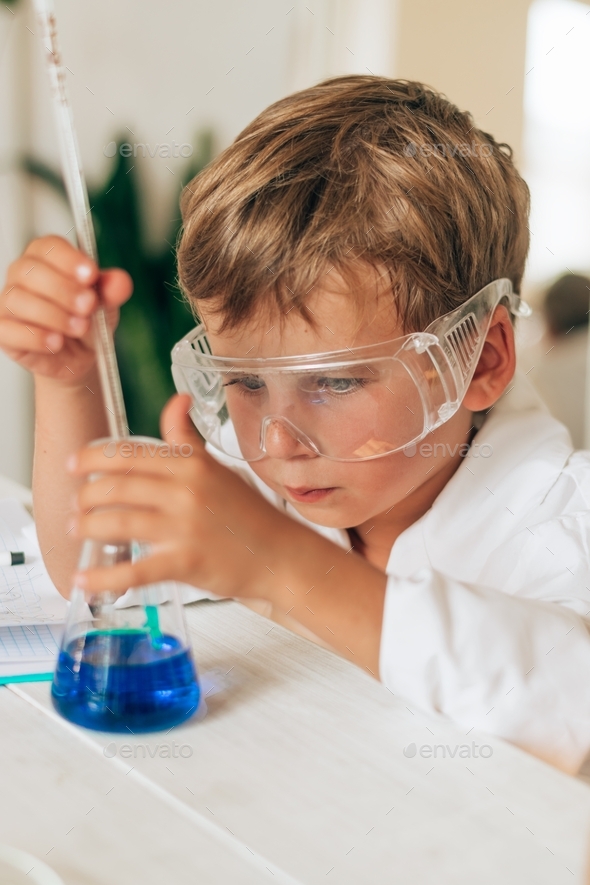 Five-year-old boy in a white uniform doing chemical experiments in the ...