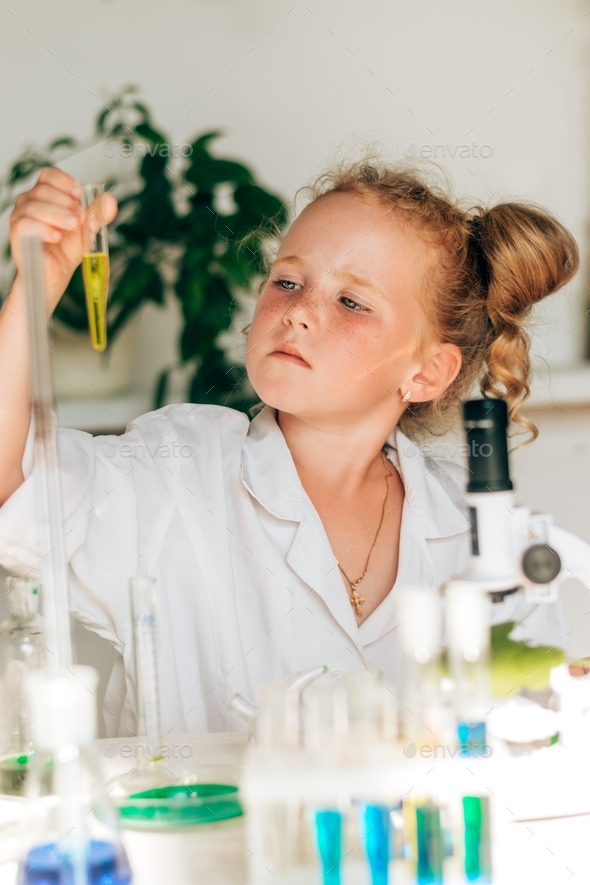 Seven-year-old girl in a white uniform doing chemical experiments in ...