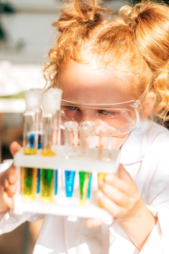Seven-year-old girl in a white uniform doing chemical experiments in ...