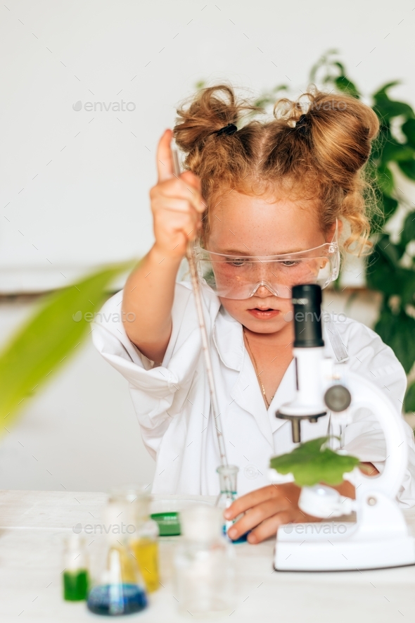 Seven-year-old girl in a white uniform doing chemical experiments in ...