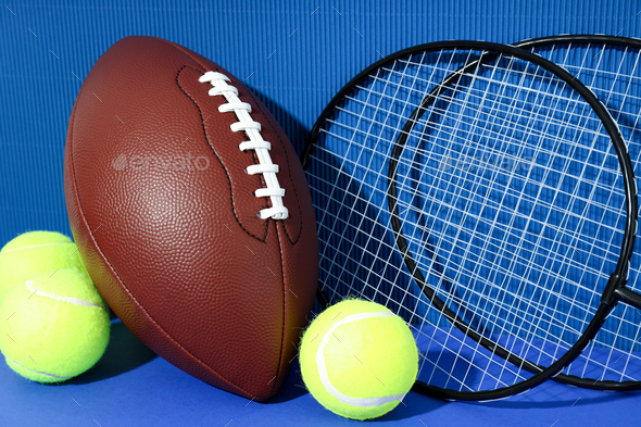 Badminton rackets, tennis balls, and basketball ball on blue background ...
