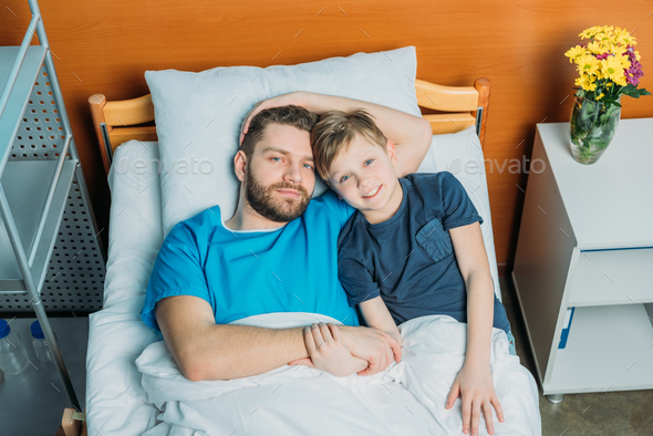 father with son embracing while laying on hospital bed at ward, dad and ...