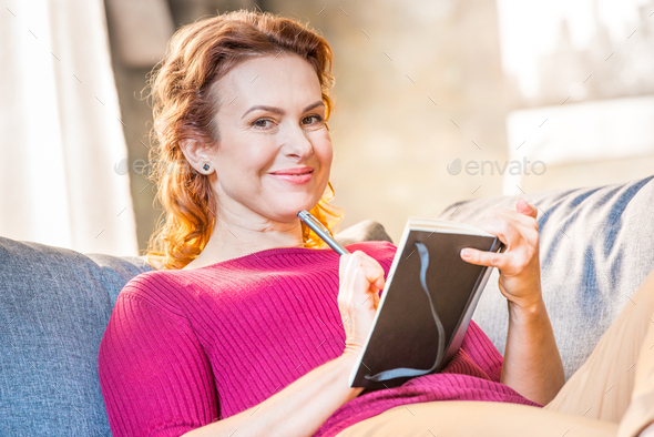 Portrait of smiling woman making notes in notepad Stock Photo by ...