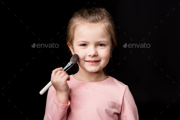 Smiling little girl applying facial powder with makeup brush isolated ...