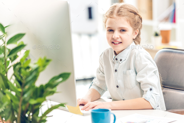 Little girl pretending to be businesswoman and working with computer in ...