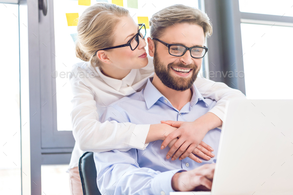 businesswoman and businessman with eyeglasses hugging and working with ...