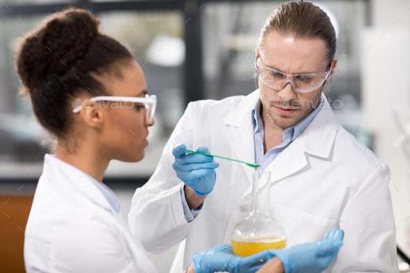 side view of concentrated scientists making experiment in laboratory ...