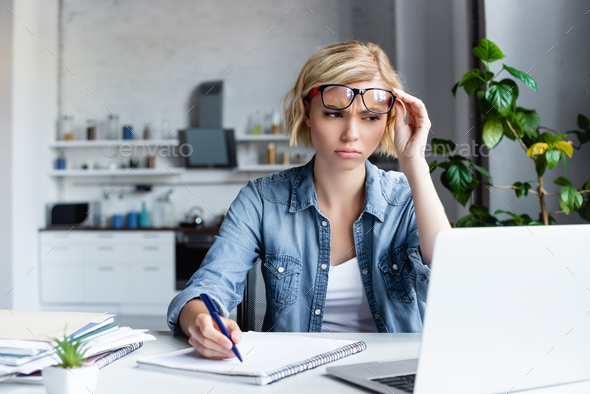 confused blonde woman making notes in notebook Stock Photo by ...