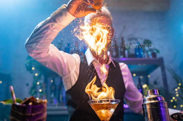 Bartender making a fire flame cocktail in a elegant night club party ...