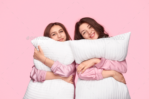 Young women hugging soft pillows during sleepover Stock Photo by kegfire