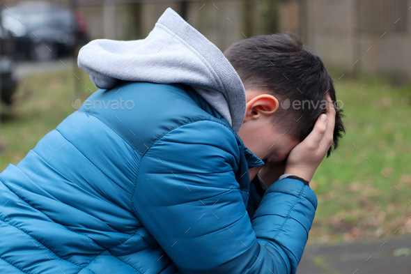 Sad teen boy 11 years old wearing gray hoodie and blue jacket in ...