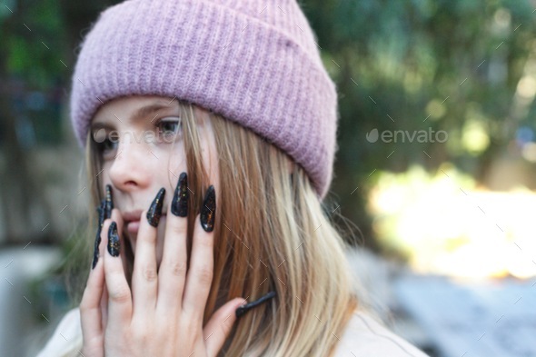 Portrait of a girl with a purple beanie hat and long black nails Stock ...