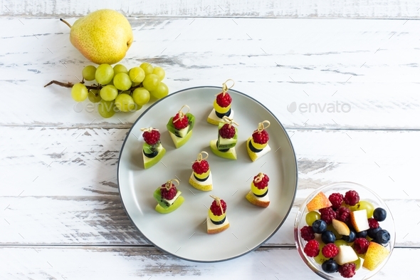 assortment of fruit canapes on a plate against the background of a ...