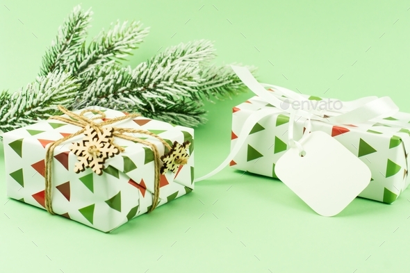 packaged gifts in festive paper on a green background with a branch of ...