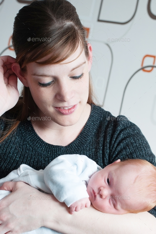 young beautiful mother smiling with a red-haired baby in her arms ...