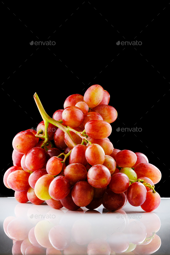 Shiny bunch of ripe red grapes isolated on black and white background Stock Photo by skumer