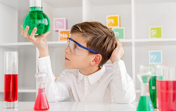Focused boy studying bright liquid in class Stock Photo by kegfire