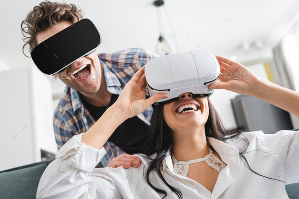 Cheerful couple using virtual reality headsets at home Stock Photo by ...
