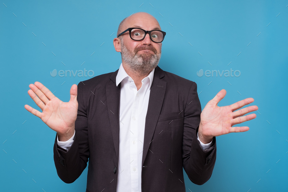 Confused man standing with raised arms and looking at camera having no ...