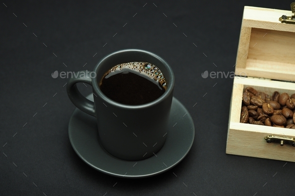 A cup of black natural coffee and coffee grain in a wooden box, on a ...