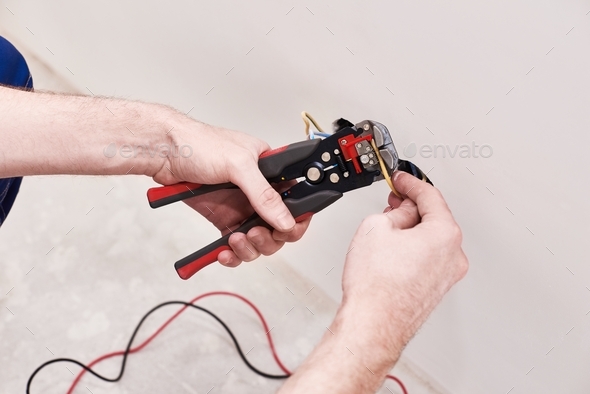 Hands man make connection terminal wire, hold crimping pliers. Wall and ...