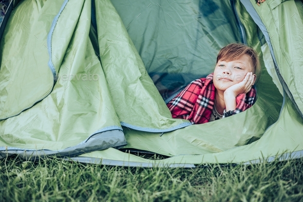 Brooding teen boy lying with plaid in camping tent. Family weekend ...