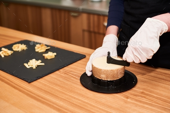 Woman selling cheese and cutting rosettes of Swiss monk cheese with ...