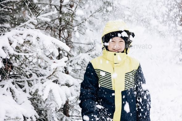 Winter portrait of happy teenager boy looking snow falling down in ...