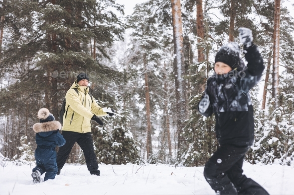 Father and sons having fun snowball fight together Happy children ...