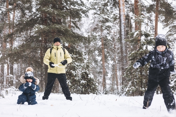 Father and sons having fun snowball fight together Happy children ...