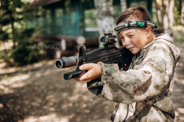Teenager boy with weapon in his hand playing laser tag shooting game in ...