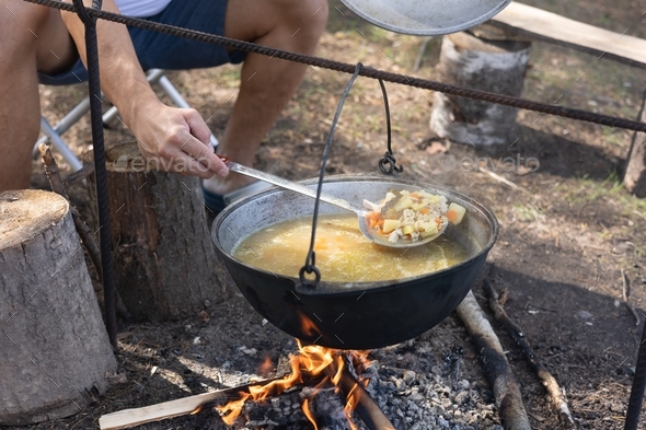 Cooking soup in cauldron on open fire in nature. Bowler on bonfire in ...