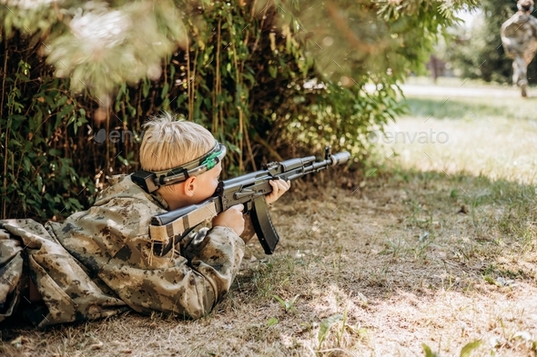 Teenager boy in camouflage with a weapon in his hand playing laser tag ...