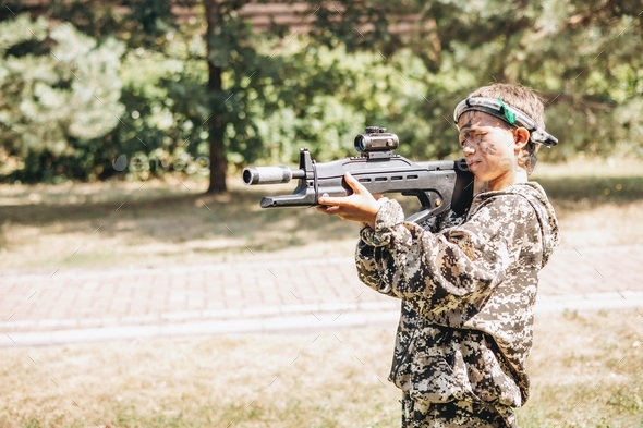 Teenager boy in camouflage with a weapon in his hand playing laser tag ...