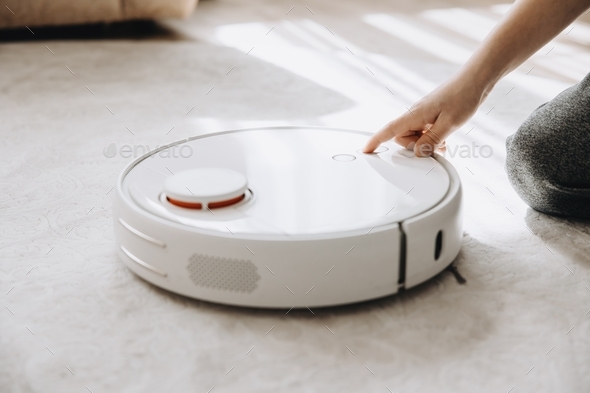 Close up of boy hand push start button on robotic vacuum cleaner for ...