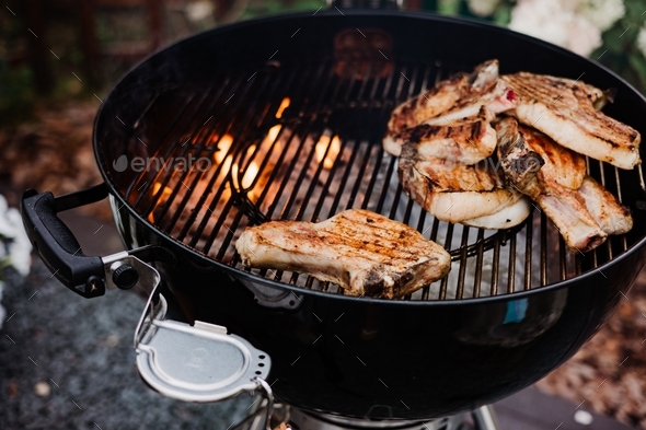 Backyard BBQ. Close-up of grilling steaks of meat on barbecue with ...