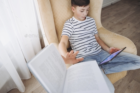 Teenage boy sitting on couch using tablet playing video games. Child ...