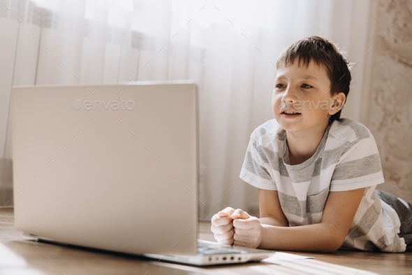 Teenage boy lying on floor using laptop having video chats. Online ...
