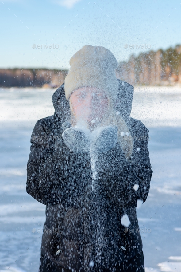 Happy teenage girl playing with snow on ice. Stock Photo by akifewas