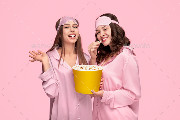 Cheerful female friends eating popcorn during sleepover Stock Photo by ...