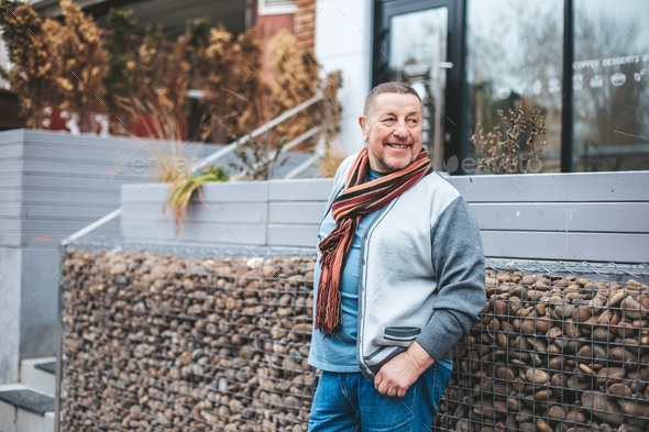 Senior man, baby boomer generation stand smiling outdoors on autumn or ...