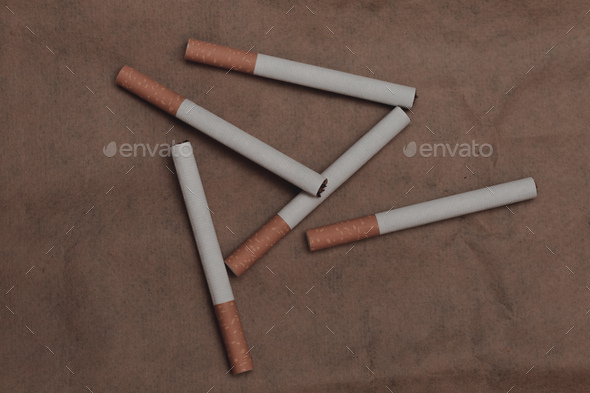 Five cigarettes laying on a brown background Stock Photo by Lemnaouer