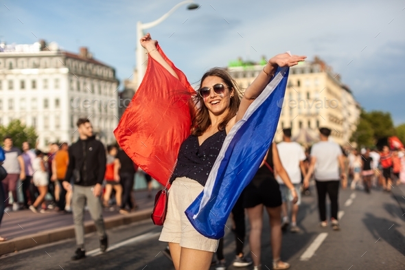 Young French woman raising her arms in the air from excitement carrying ...