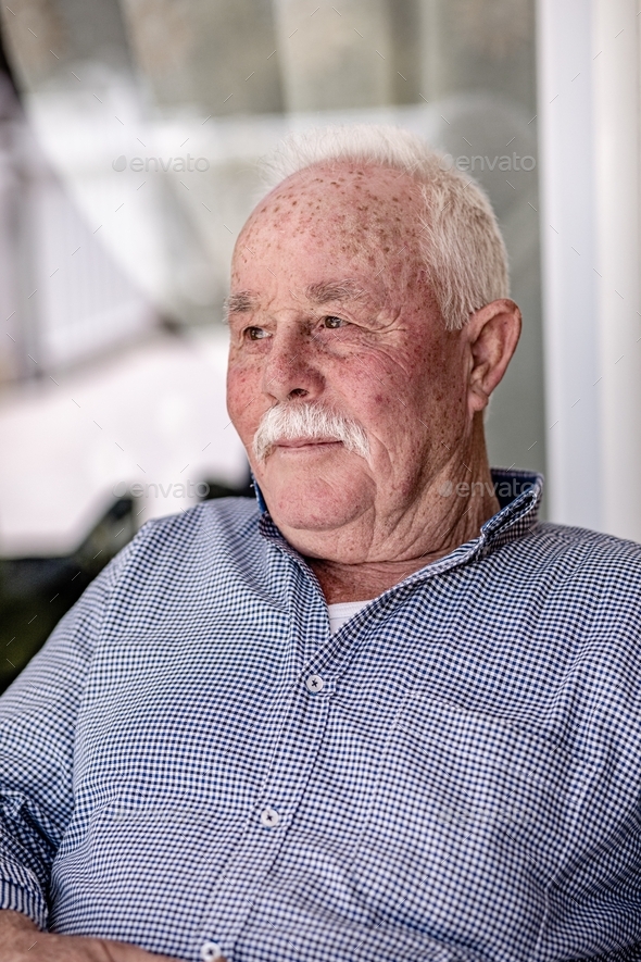 Baby boomer sitting outside looking away with a white hair and mustache ...