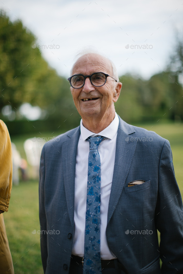 Baby-boomer wearing a blue tie and eyeglasses with a smile on his face ...