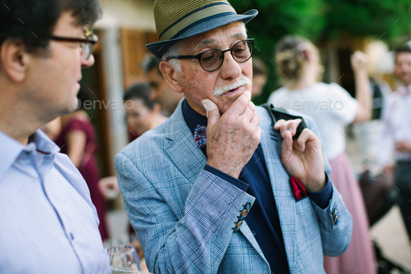 Baby-boomer wearing a hat and touching his face thinking about what to ...