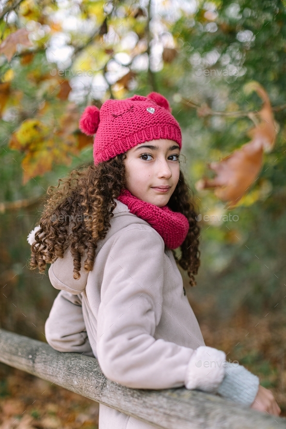 Gen z girl with curly hair leaning on a fence in the woods Stock Photo ...