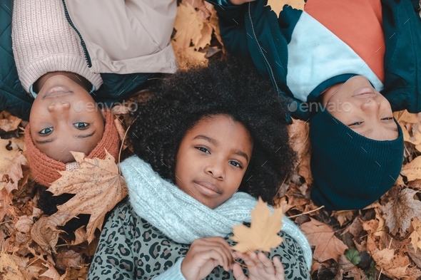 Three young diverse kids laying down on fall leaves Stock Photo by ...