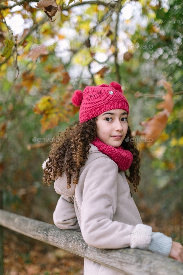 Gen z girl with curly hair leaning on a fence in the woods Stock Photo ...