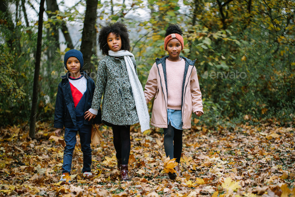 Three diverse kids walking outside in fall season Stock Photo by Lemnaouer